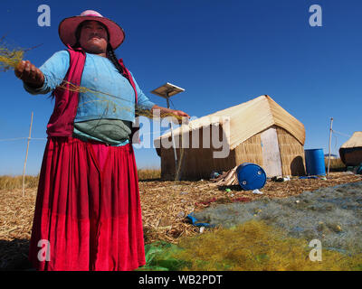 Uro woman standing up on Totora reed and watching to the lake. The Uru ...