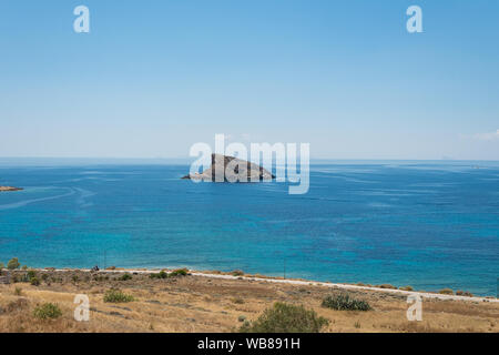 A shark fin shaped rock across komito beach at Syros greek island ...