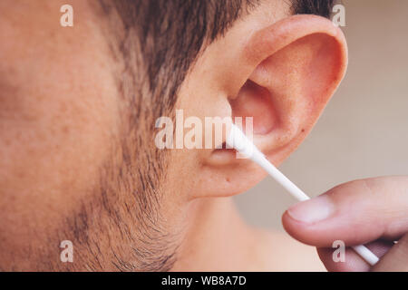 Man about to clean his ears using Q-tip cotton swab. Hygiene essentials ...