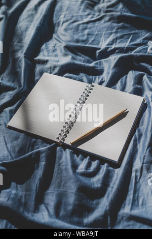 diary notebook on blue bedding; concept of journaling or brainstorming ...