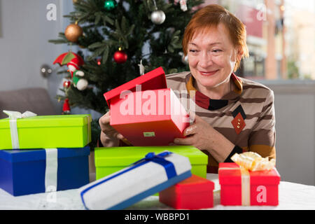 Senior woman with boxes of gifts near the New Year tree Stock Photo - Alamy