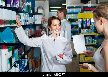 Diligent friendly female pharmacist wearing uniform working in ...
