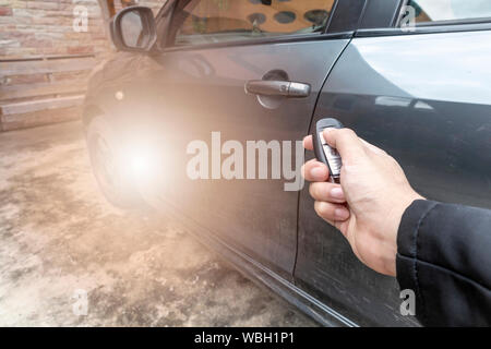 A man opening his car door with pushing button on control remote key ...