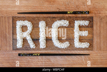 "RICE" word written with grains of rice and framed by black chopsticks ...