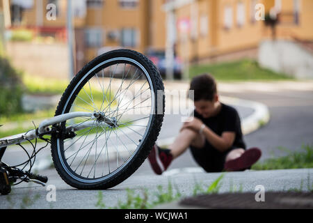 Kid hurts his leg after falling off his bicycle. Child is learning to ...