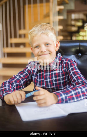 Adorable caucasian kid writing book sitting on the table shouting and ...