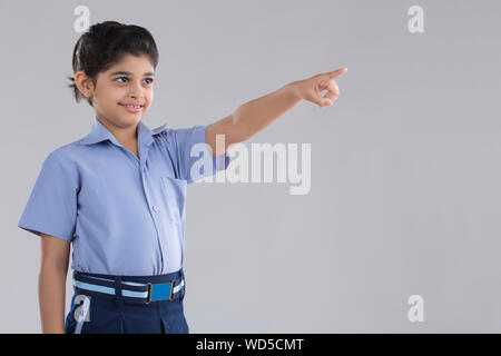 Happy indian school girl pointing advertising isolated on violet ...