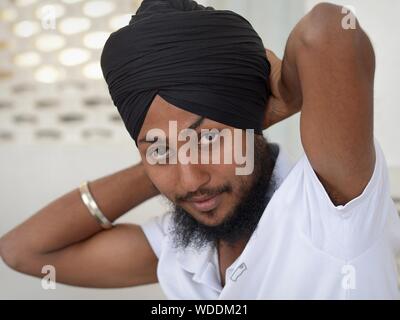Handsome young Indian Sikh devotee with black beard and smiling eyes ...