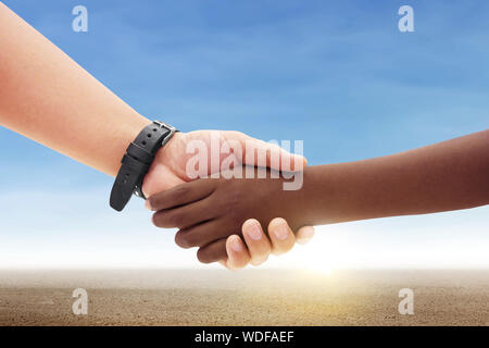 Two young men of different races shaking hands and making a thumbs-up ...