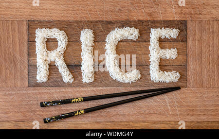 "RICE" word written with grains of rice, framed by black chopsticks ...
