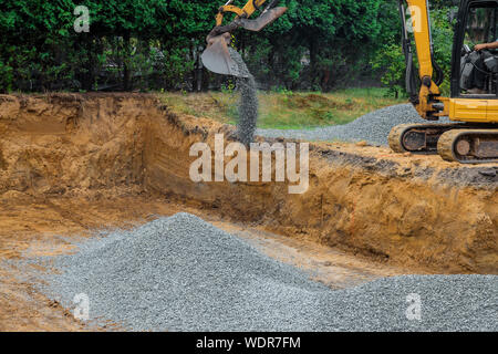 Excavator bucket backfilling trench for stone backfill of foundation ...