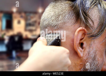 Hands of barber using scissors to cut customer's hair in salon. barber ...