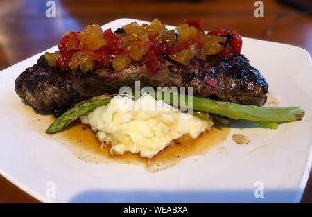 Big juicy slab of New York steak with asparagus and potato salad Stock ...
