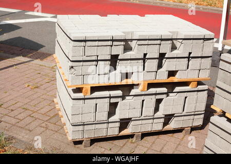 Concrete blocks stacked on pallets outdoors in front of a detached house under construction in ...