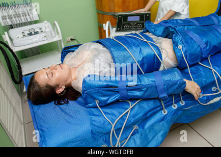 Woman in pressotherapy suit lying down having pressure therapy for ...