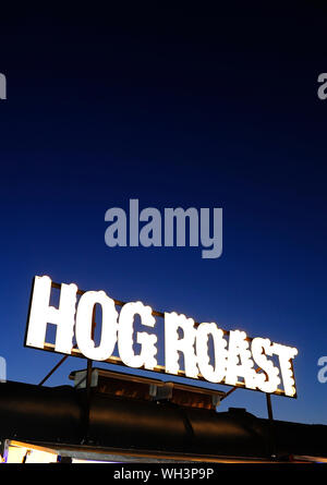 Illuminated hog roast sign on top of stall against night sky Stock ...