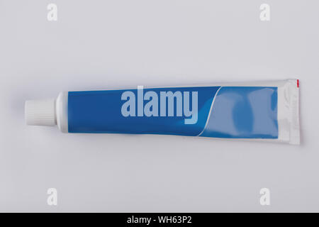 Tube of ointment on light blue background, top view. Space for text ...