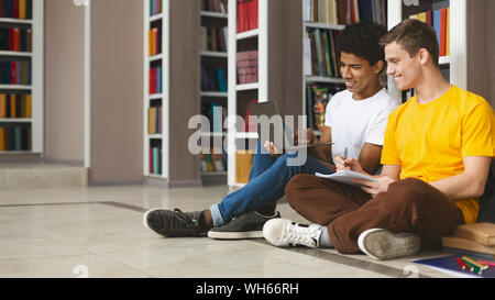 Two young guys studying on floor in library Stock Photo - Alamy