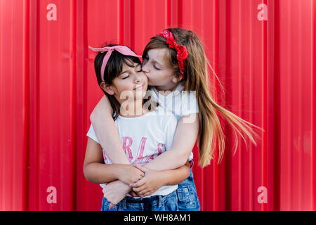 Two cute blond sisters kissing outdoors Stock Photo - Alamy