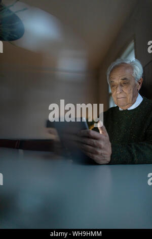 Senior man using tablet while sitting at table in home Stock Photo - Alamy