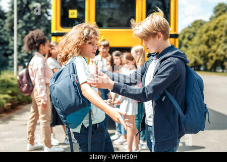 Boy bullying and pushing a group of girls in a primary school play area ...
