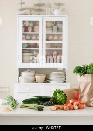 Closeup of fresh vegetables and paper bag on kitchen counter with utensils in cupboard Stock Photo Alamy