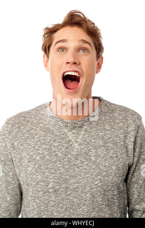 Shocked young guy standing with open mouth, pointing at empty space in ...