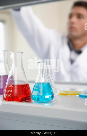 Hispanic young man working at pharmacy drugstore pointing down looking ...