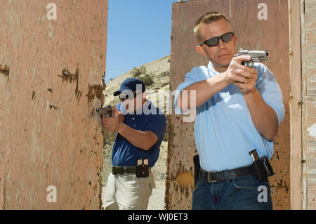 Two men aiming hand guns at firing range Stock Photo - Alamy