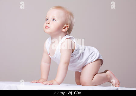 Thoughtful baby looks up, studio white background. Sad child with the ...