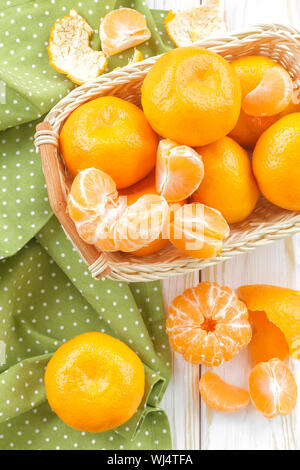 peeled and unpeeled tangerines in a basket isolated on white ...