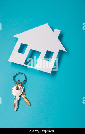 Silver key with silver house figure on white wooden background, buying ...