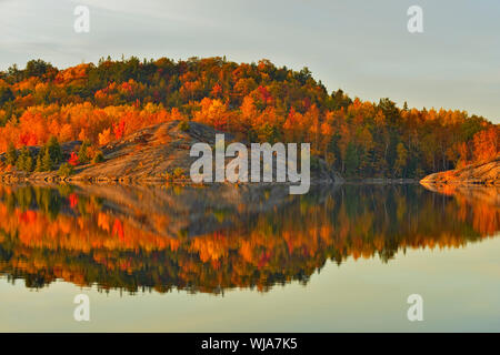 Autumn colour reflected in Simon Lake at dawn, Greater Sudbury, Ontario ...