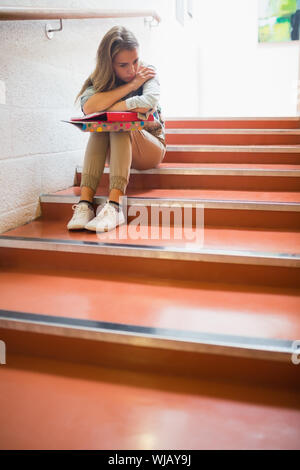 Young depressed lonely female college student walking down the stairs ...