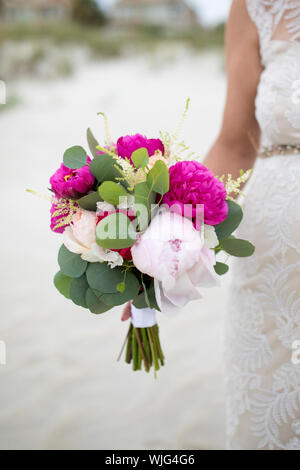 A closeup shot of bride hands with pink nail polish and a sparkly ring ...