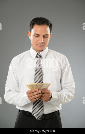 Indian man counting hundred rupees banknotes Stock Photo - Alamy