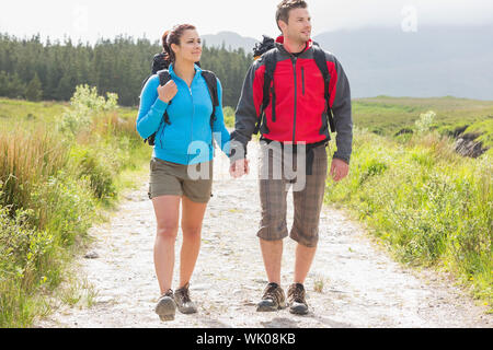 Hikers with backpacks holding hands and walking Stock Photo - Alamy
