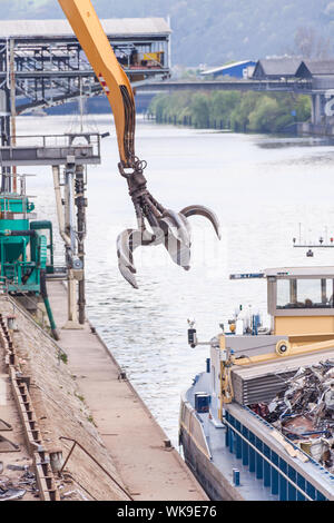 Open barge being loaded or offloaded at a wharf on an urban waterway or ...