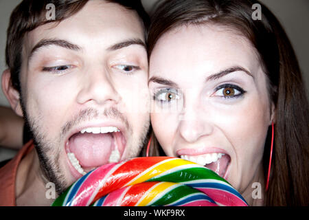 Cute Couple Biting into Big Colorful Lollipop Stock Photo - Alamy