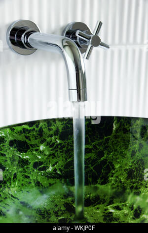 Contemporary bathroom water running out of beautiful designer wall mounted faucet into tempered glass fake green marble vessel sink Stock Photo Alamy
