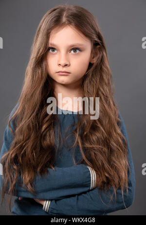 Thinking pupil kid girl with folded arms thinking and serious looking ...
