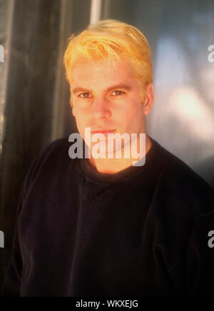 Stock photo of portrait of young blonde curly girl against the wall ...