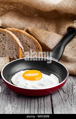 Frying pan with tasty fried quail eggs, sausages and bread on dark ...