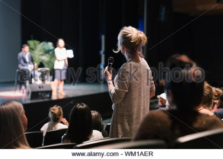 Businesswoman in audience asking question at business conference Stock ...