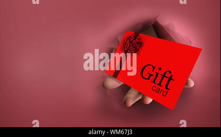 Hand bursting through paper against red vignette Stock Photo - Alamy