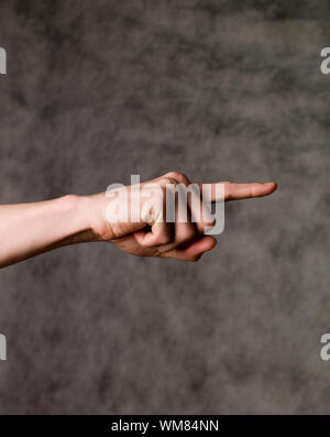 Pointing finger towards grey background Stock Photo - Alamy