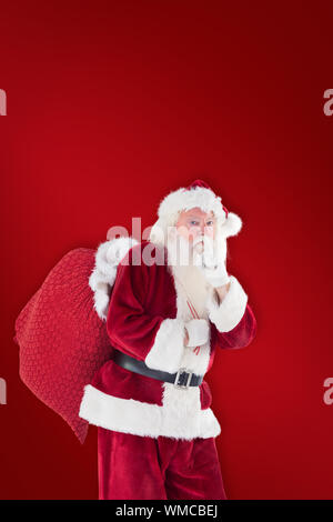 Santa asking for quiet with bag against red background Stock Photo - Alamy