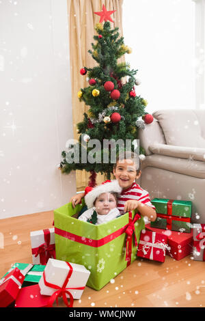 Portrait of siblings sitting against christmas tree at home Stock Photo ...