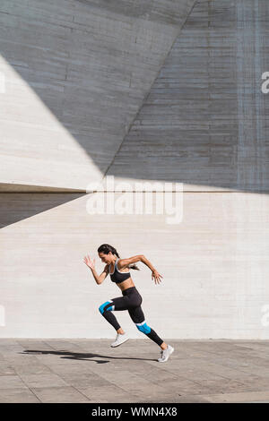 Female athlete sprinting on a running track in a stadium. Female runner ...