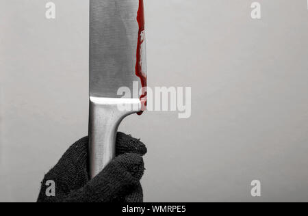Hand of a murderer or killer soaked in blood and holding a knife ready ...